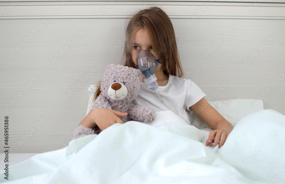 Sick child is sick at home, lying in bed with teddy bear. Does the ...