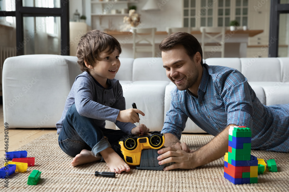 Happy adorable little child son fixing toy car with screwdriver ...