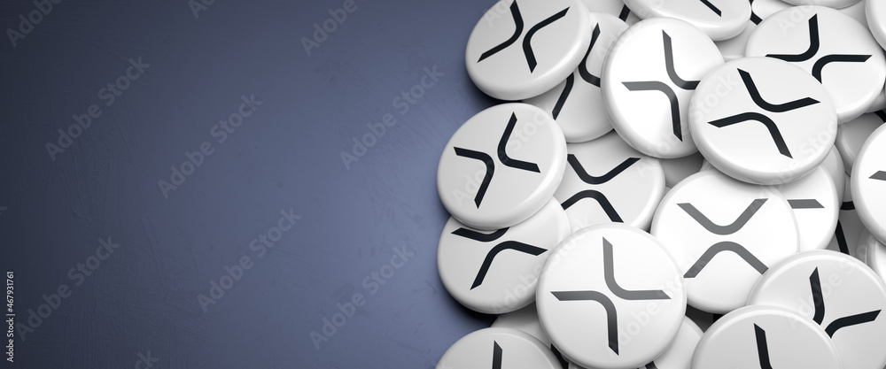 Logos of the cryptocurrency Ripple (XRP) on a heap on a table. Copy ...