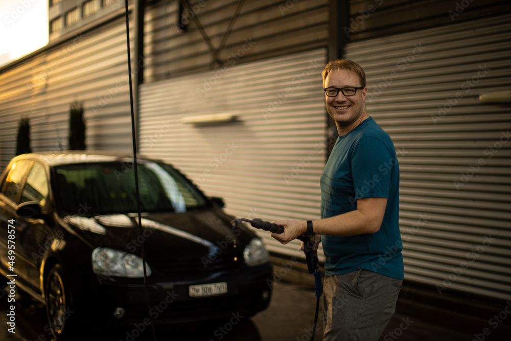 Young man washing his beloved car carefully in a manual car wash to ...