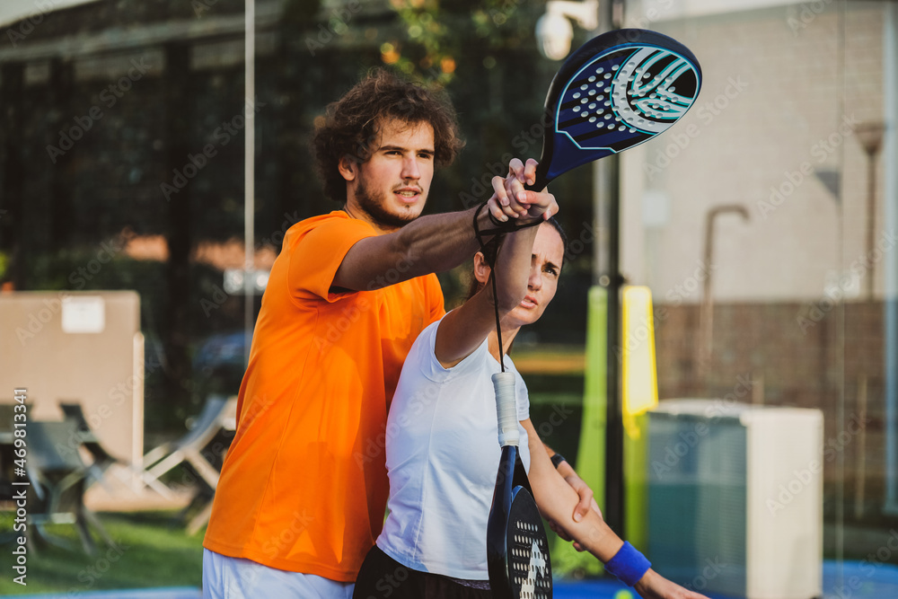 Young teacher is monitoring teaching padel lesson to his student ...
