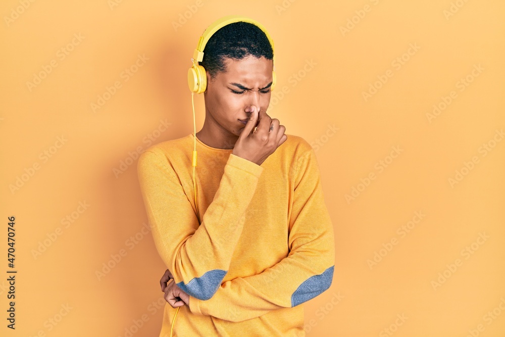 Foto Young african american guy listening to music using headphones ...