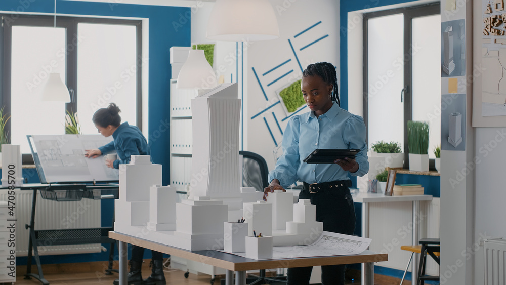 Architect using digital tablet to design layout of building model and ...