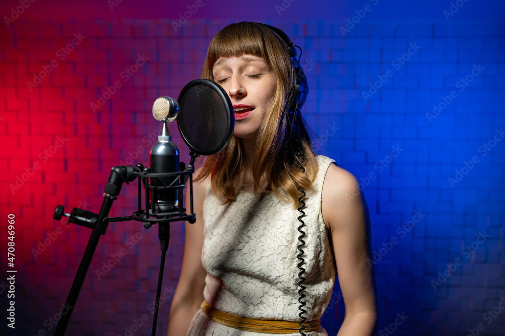 Young pretty singer in headphones closed her eyes. Woman performs song ...