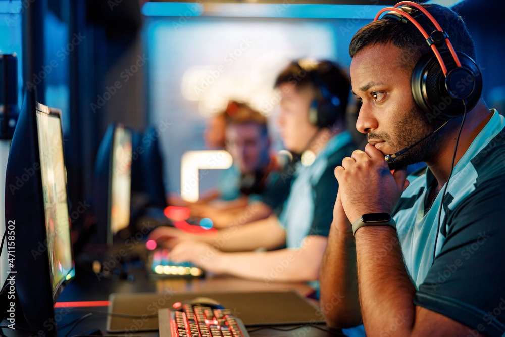 Side view of focused African professional gamer wearing headphones ...