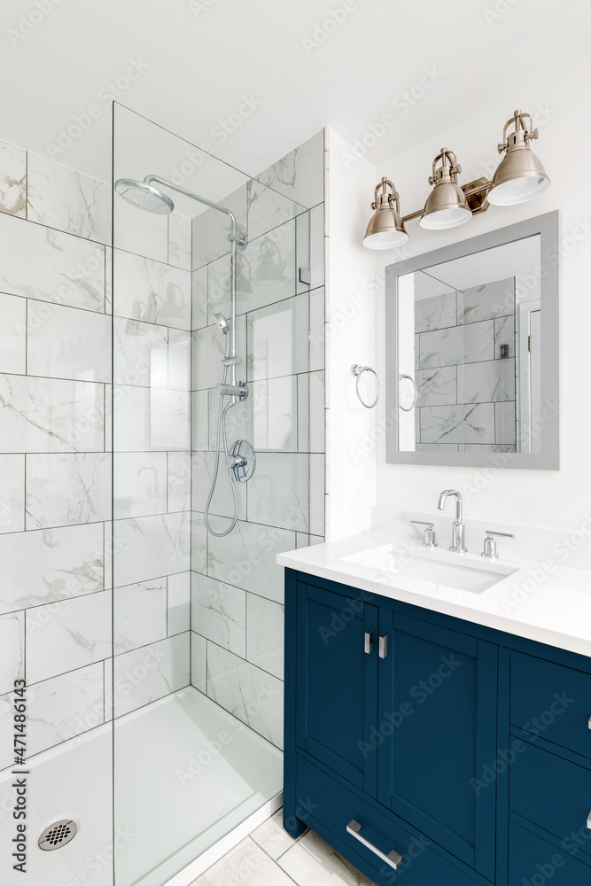 An elegant, remodeled bathroom with a navy blue vanity and bronze ...