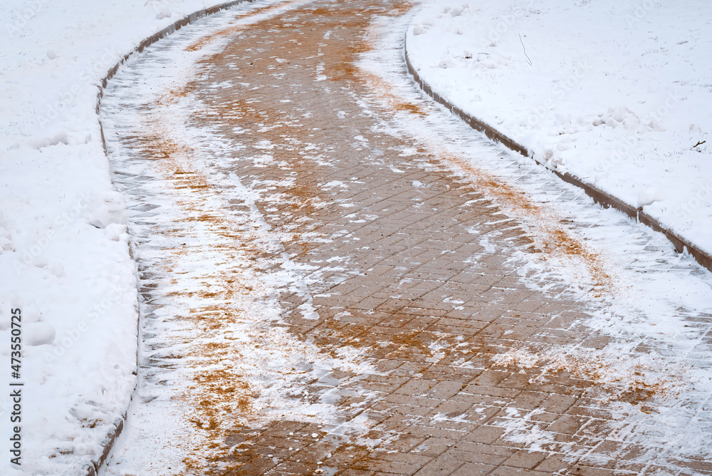 Paving slabs sprinkled with salt and sand mixtures. De-icing chemicals ...