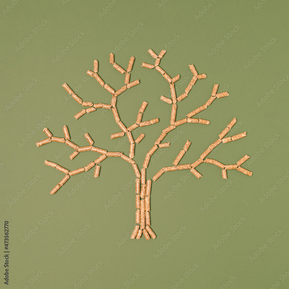 Wooden pellet tree shaped layout on a natural green background. Ecology ...