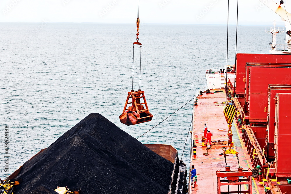 Loading coal from cargo barges onto a bulk carrier using ship cranes ...