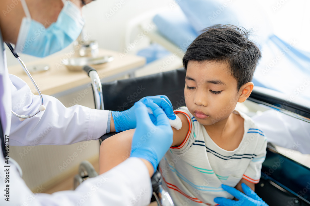 asian boy sitting on a wheelchair to receive an injection from a male ...