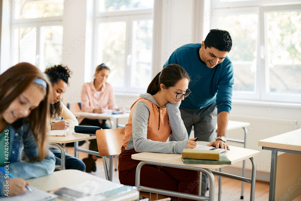 Female high school student learns with teacher's help in classroom. Stock Photo | Adobe Stock