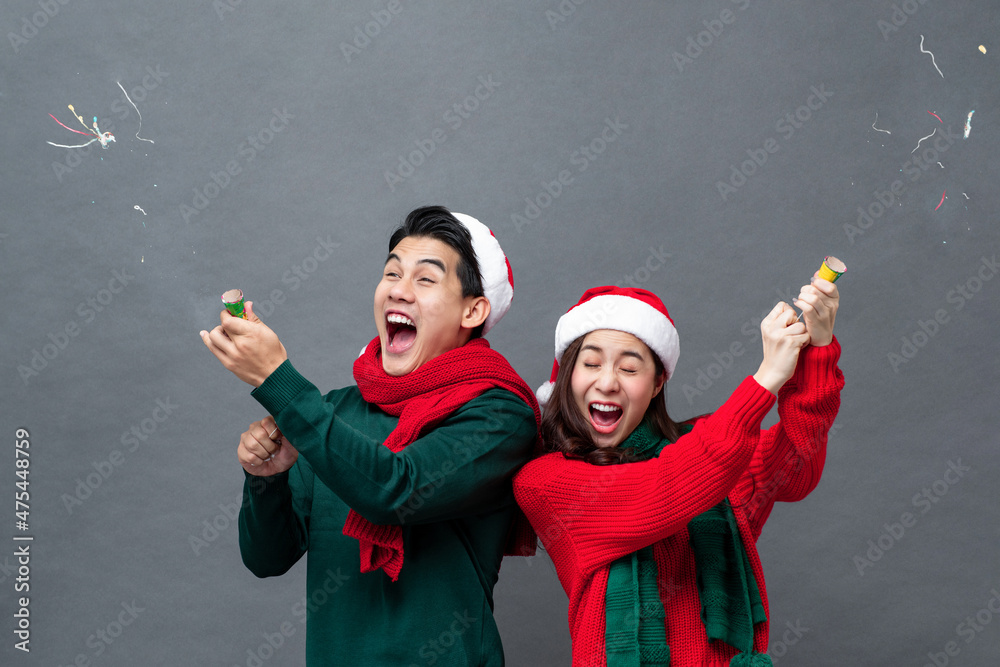 Happy excited Asian couple pulling party poppers celebrating Christmas ...