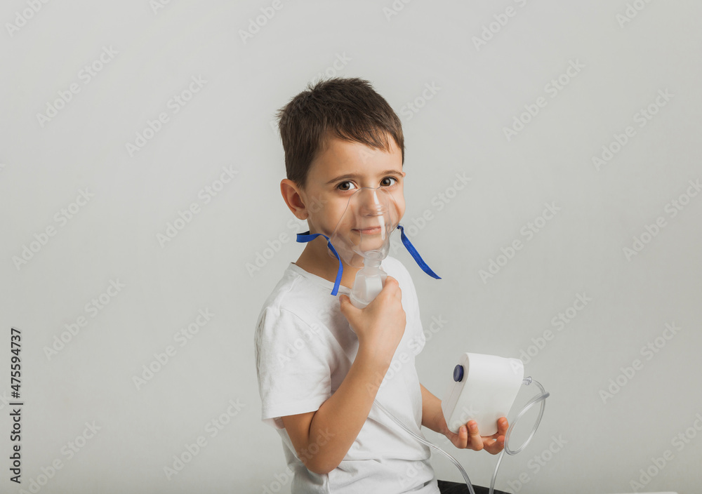 Cute little boy makes inhalation. The child holds an inhaler in his ...