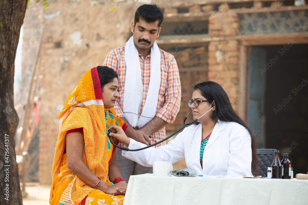 Indian Female doctor with stethoscope checking patient heart beat or ...