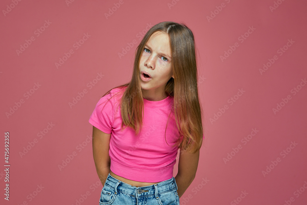 Displeased child girl frowning, asking what do you want on pink studio ...
