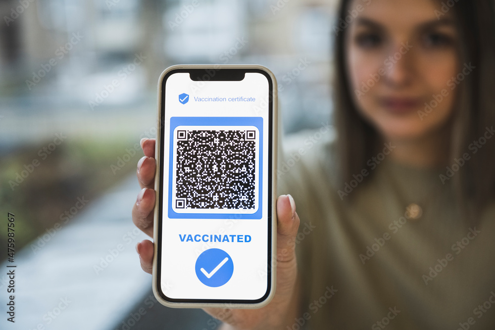 Woman holding mobile phone with QR code and check mark symbol on screen ...