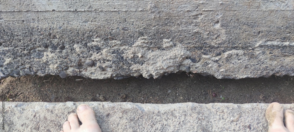 Man's big toes on concrete. A shallow crevice between two concrete ...