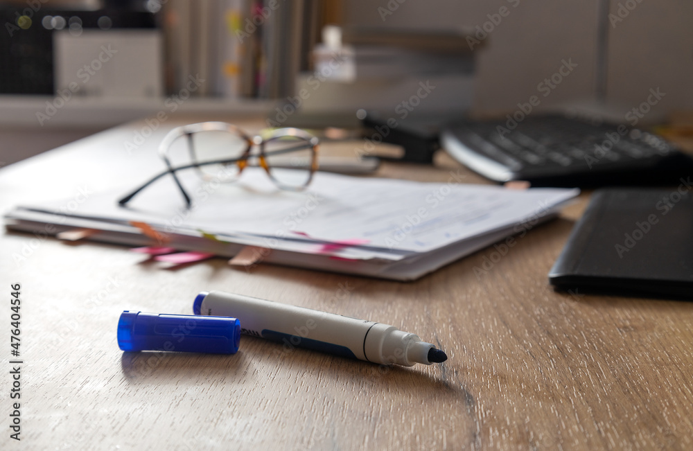 Closeup of blue marker for grammar correction.Pile of text paper ...