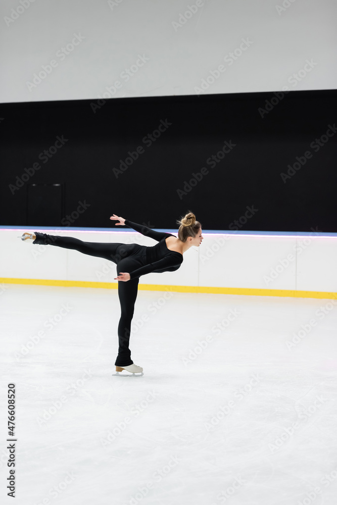side view of professional figure skater in black bodysuit skating with ...