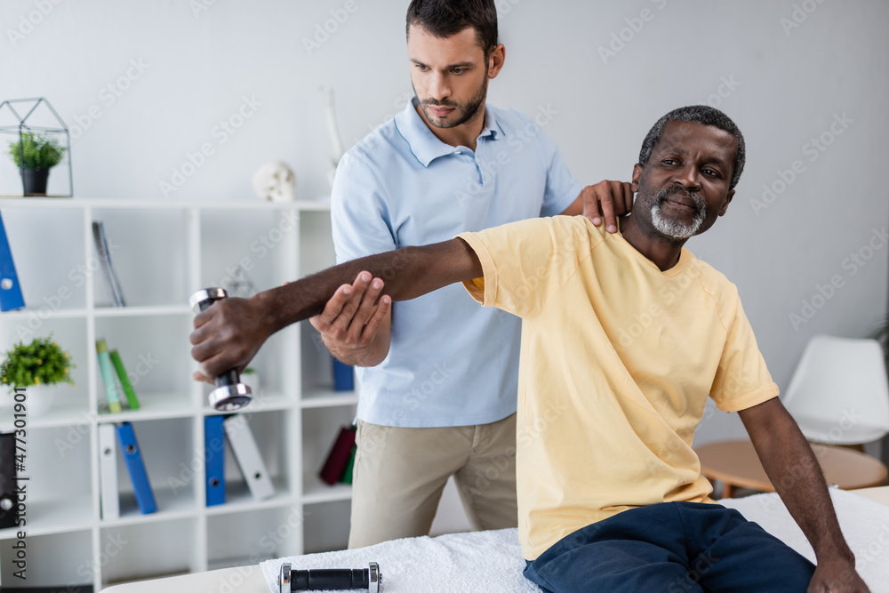 hospital trainer assisting mature african american patient training ...
