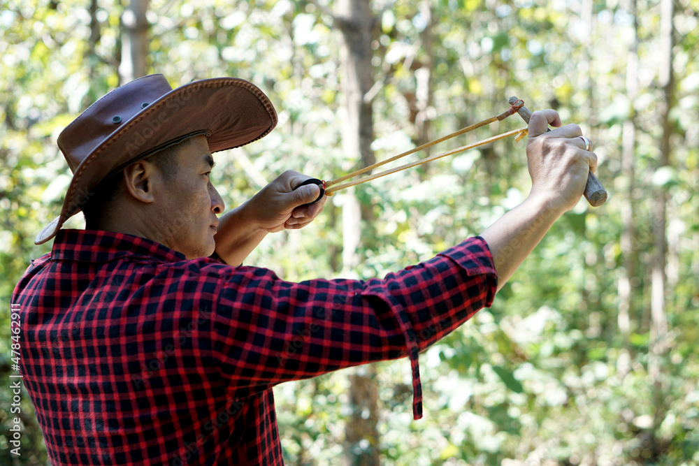 Asian man shooting a slingshot to shoot seeds into the forest Concept ...