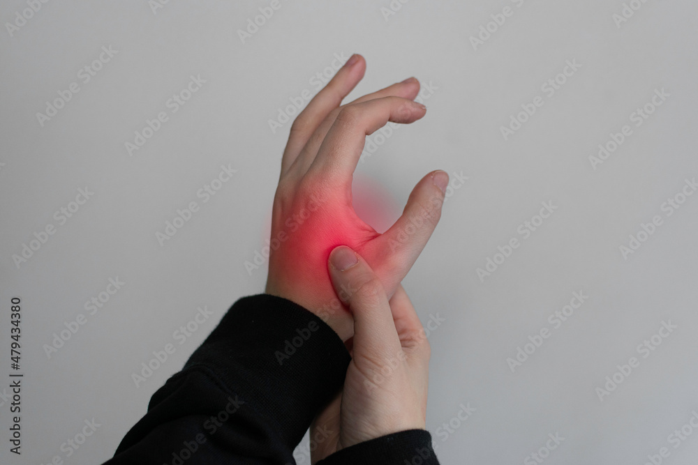 Young female suffering from pain in hands and massaging her painful ...