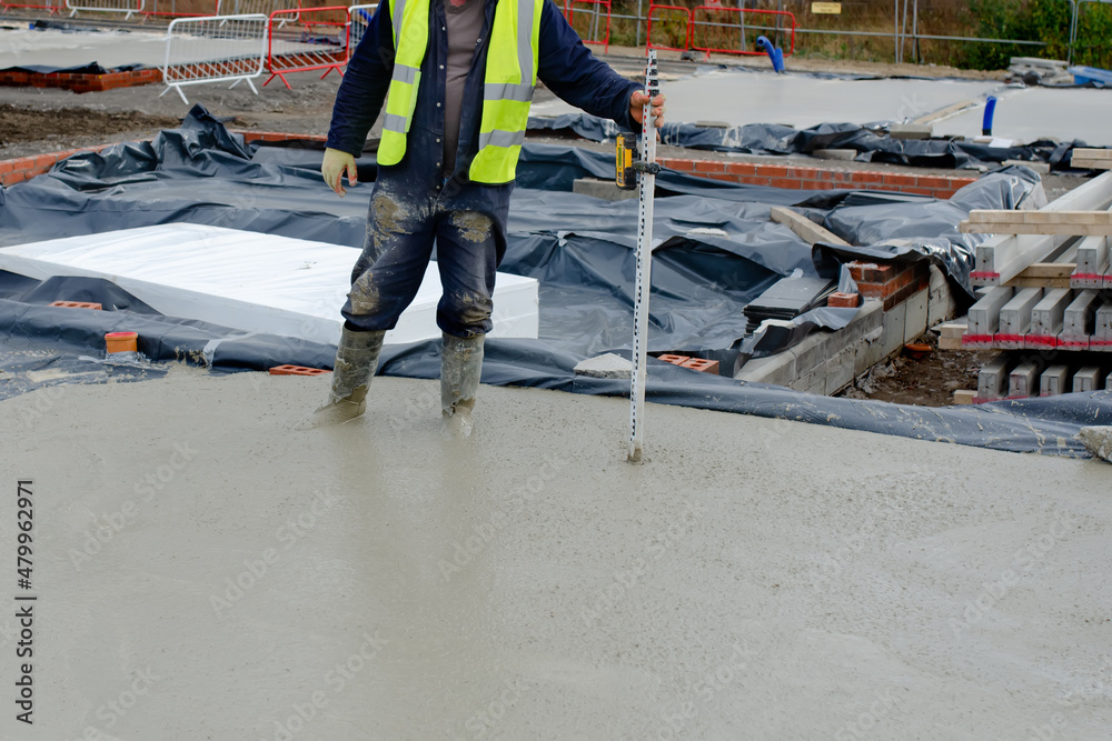 Concreter checking level of the concrete using laser level and staff as ...