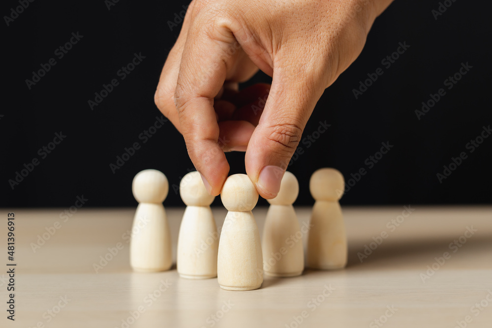 Wooden figures human was chosen leadership of teamwork. man's hands are ...