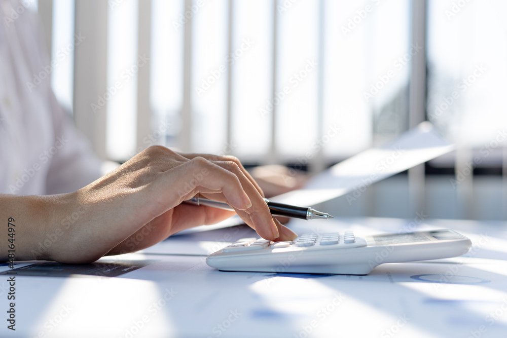 A business woman using a calculator to calculate numbers on a company's ...