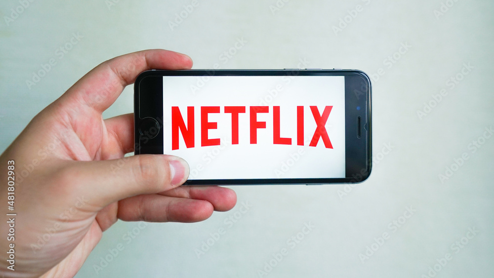 Men use Netflix app on smart phone screen. Netflix is an international ...