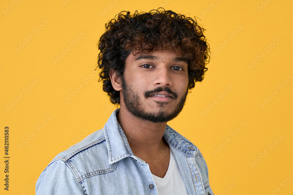 Young curly smart indian cool guy standing isolated on yellow ...