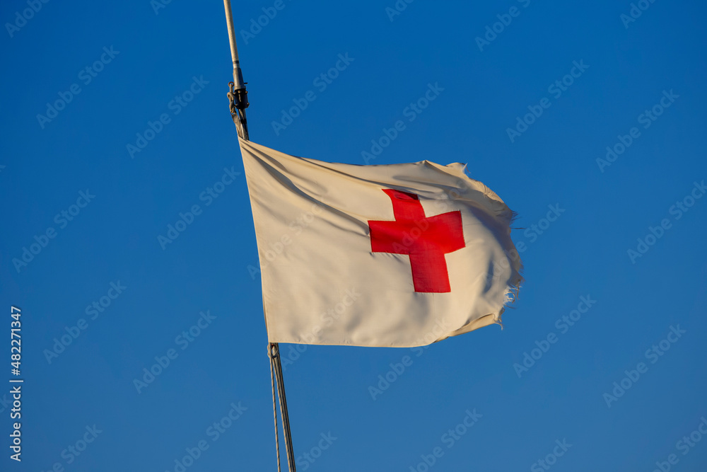 Drapeau de la croix rouge usé par le vent et avec un grand ciel bleu ...