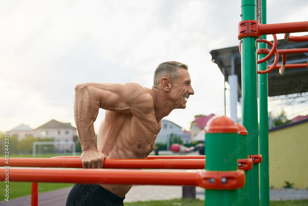 Side view of caucasian male athlete doing exercises for arms on ...