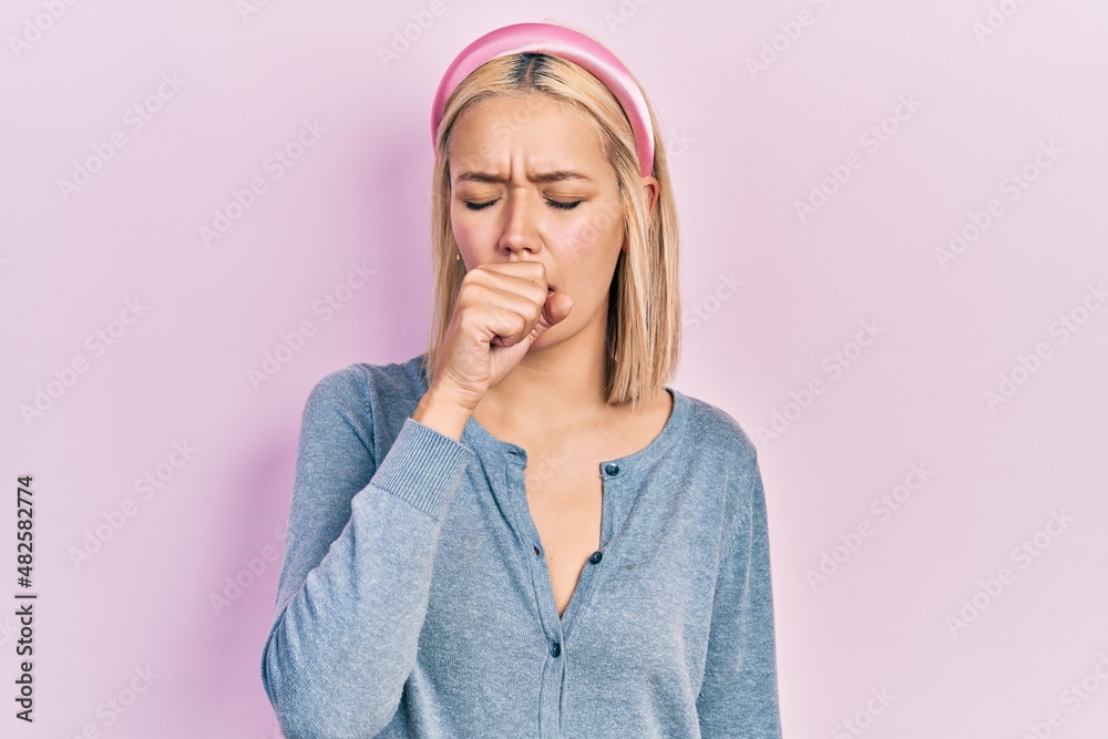 Beautiful blonde woman standing over pink background feeling unwell and ...