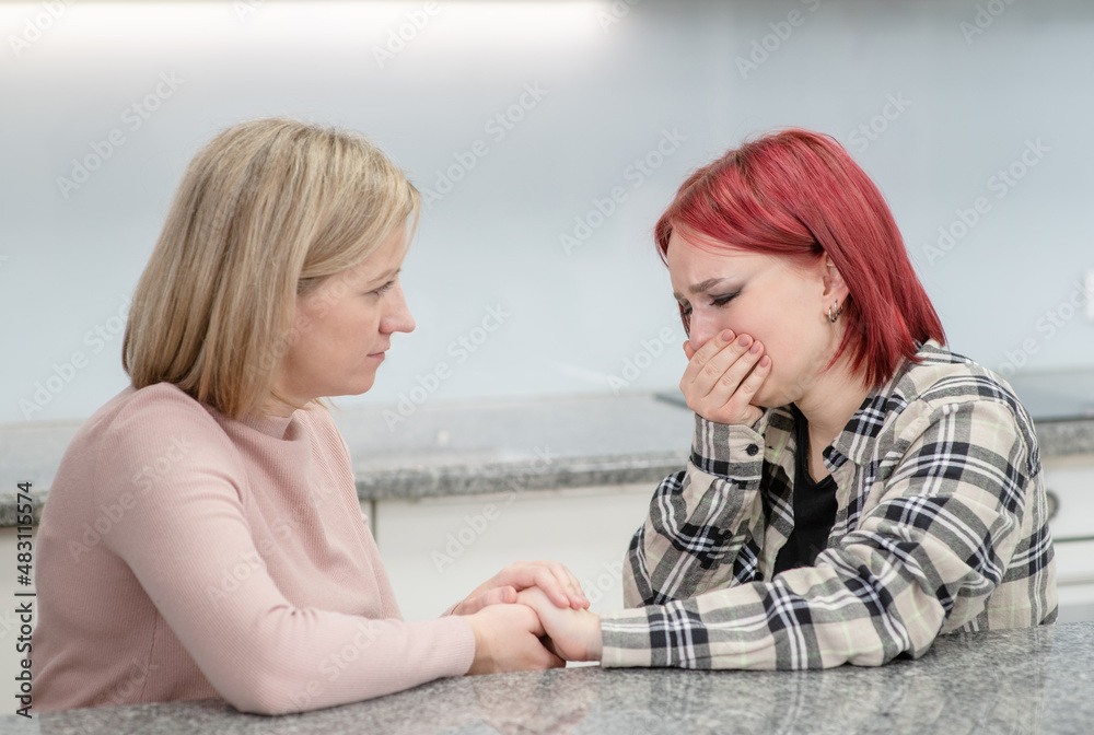 Careful mother and teen girl talk together, worried parent calms crying ...