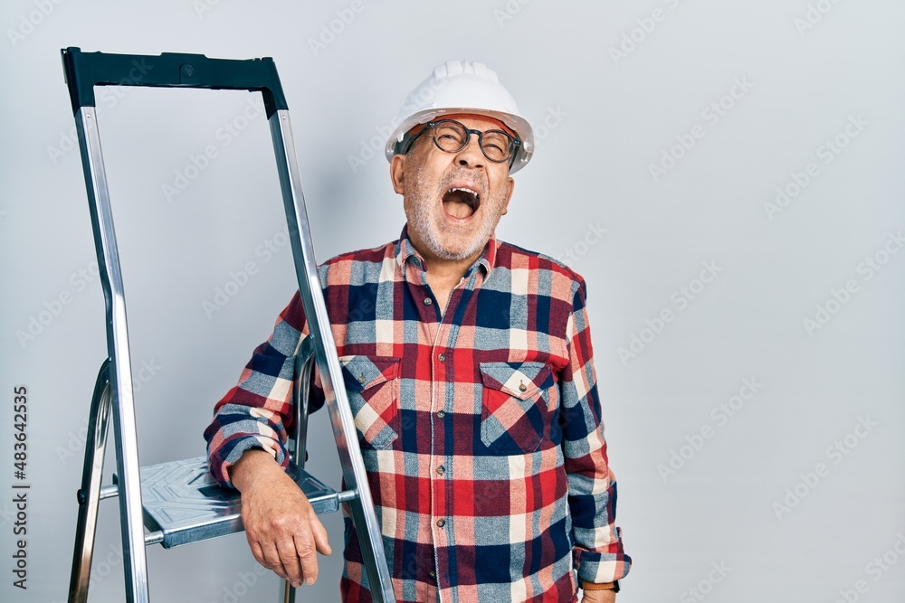 Handsome mature handyman close to construction stairs wearing hardhat ...