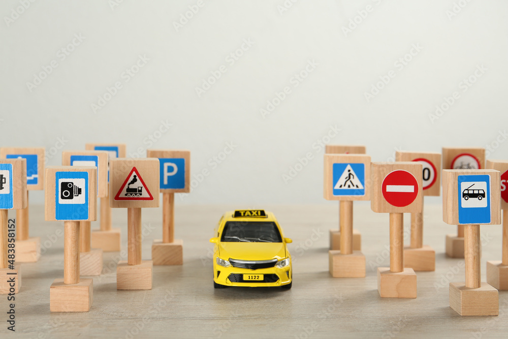Many different miniature road signs and car on wooden table, space for ...