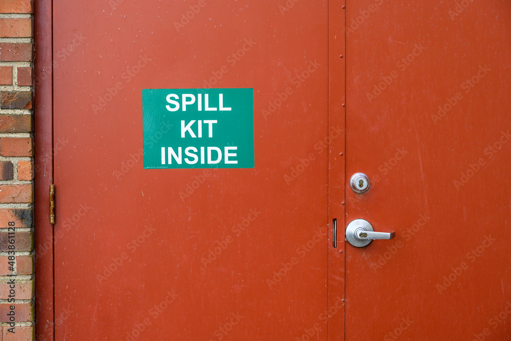 Closeup of double red metal door with green sign for spill kit inside ...
