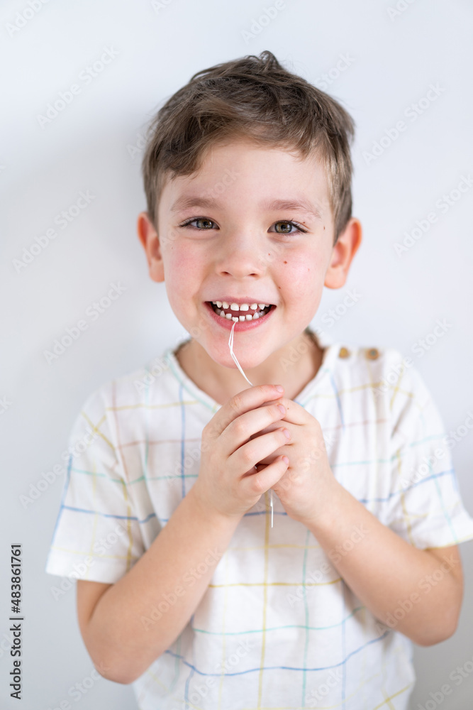 Cute boy pulling loose tooth using a dental floss. The boy's first milk ...