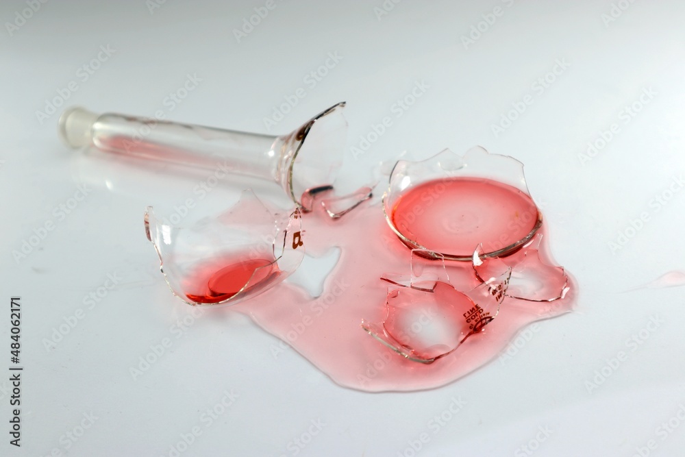 Broken laboratory glass, red liquid chemical spilled from laboratory ...