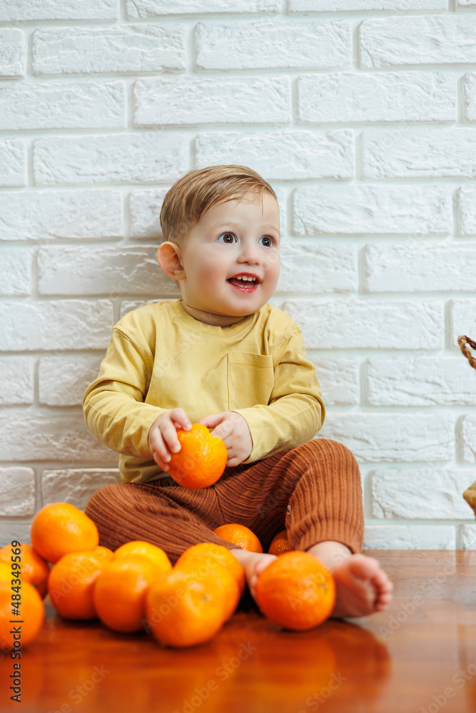 Little boy 2 years old eats tangerines. The kid wants to sit on citrus ...