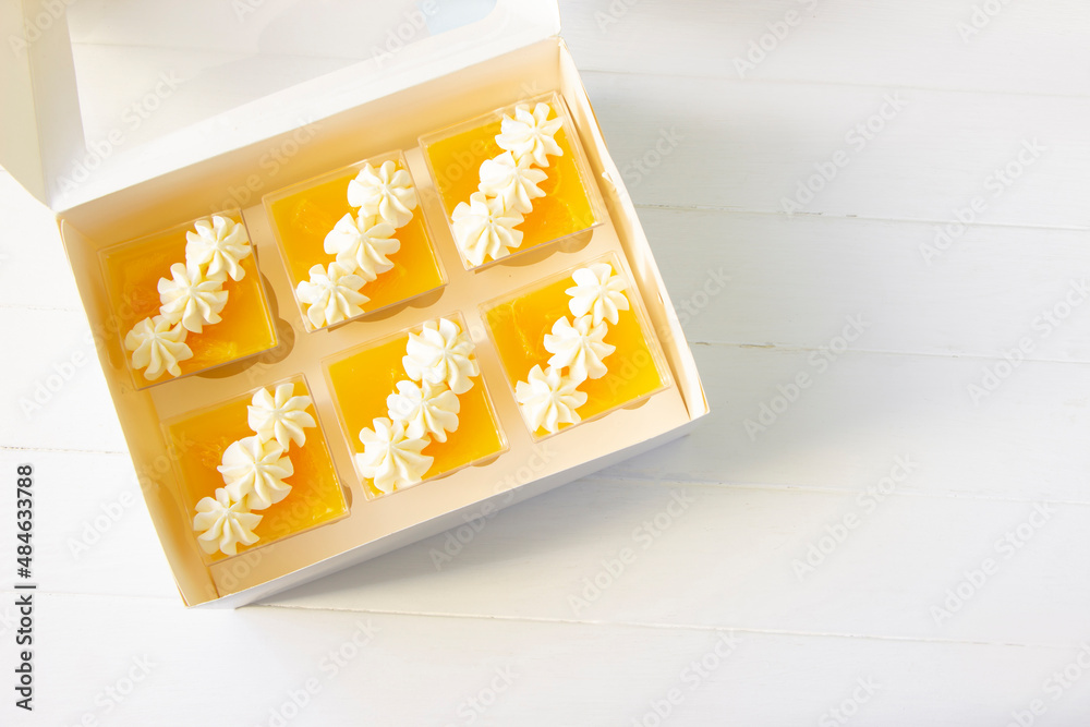Orange panna cotta in a portion cups, paper box, sweets delivery ...