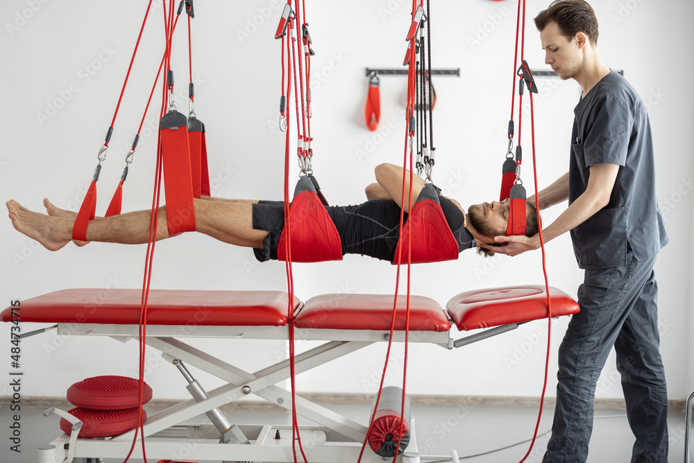 Rehabilitation specialist doing active treatment on suspension straps ...