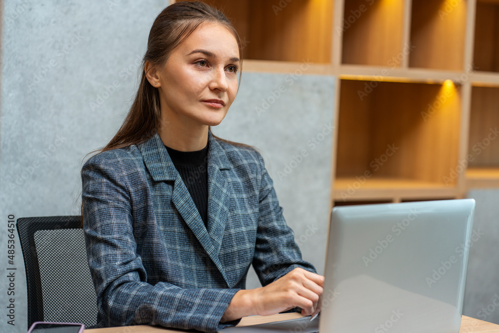 beautiful secretary sits typing on a laptop, focusing on her work ...