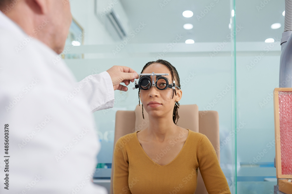 Doctor covering eyes of patient wearing trial frames and asking to read ...