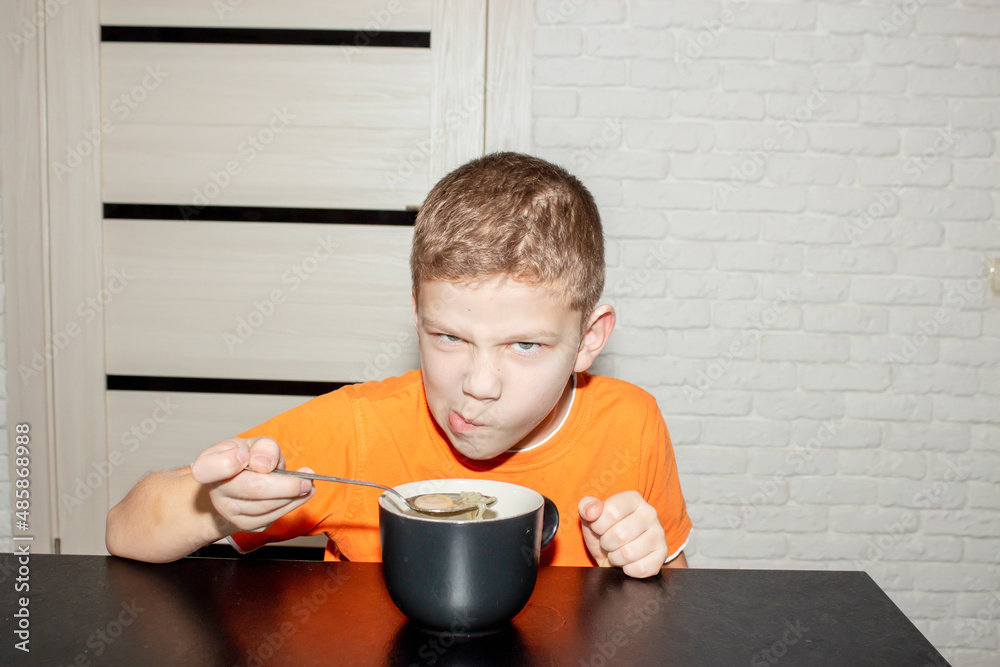 Naughty boy eats at the table. The boy does not like the food, he gets ...