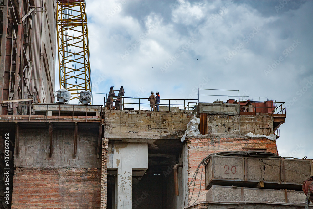Demolition of old outdated Soviet cement plant. Workers on the roof ...