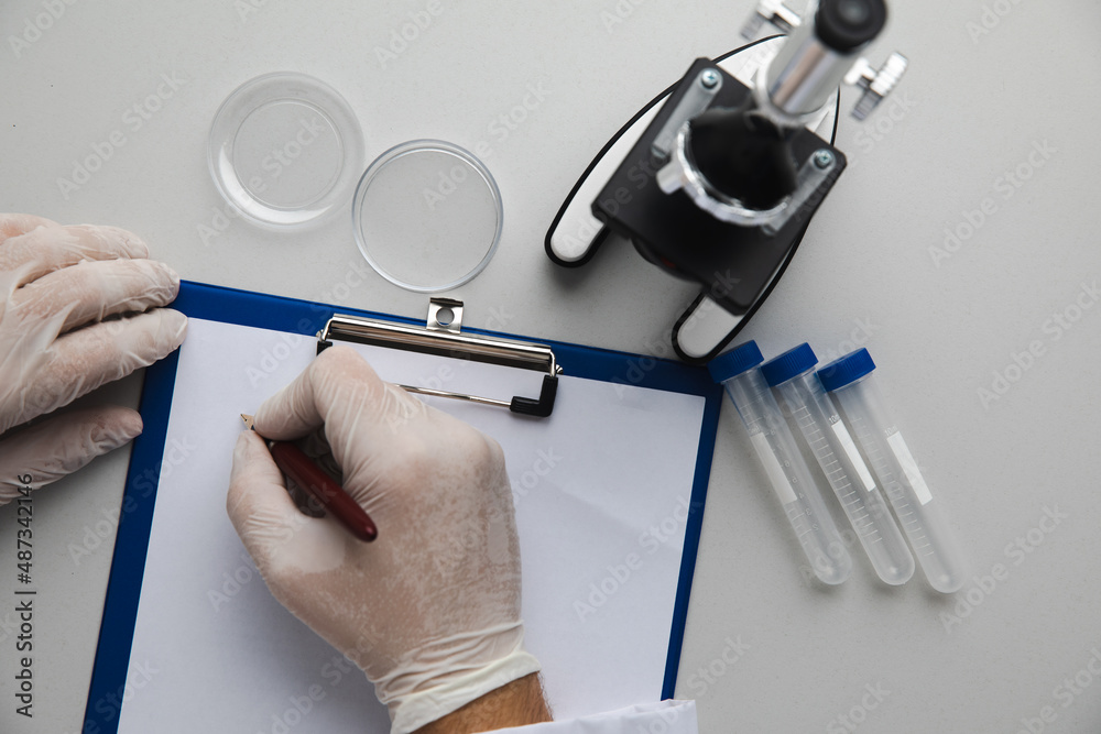Hands of medical doctor making notes at his office, test-tubes and ...