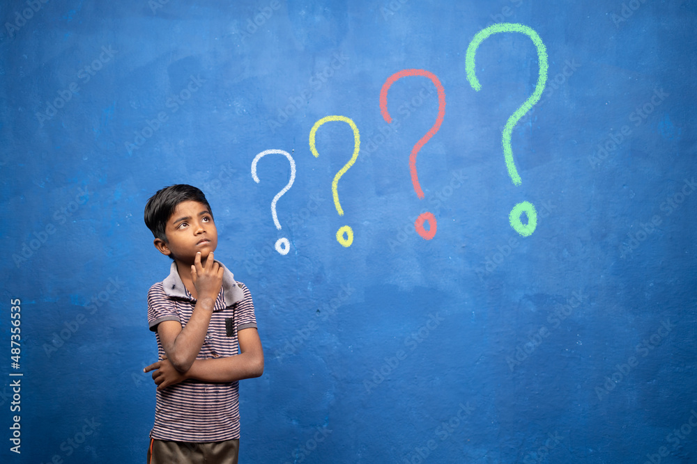 Poor Indian kid deep thinking on blue studio background with big ...
