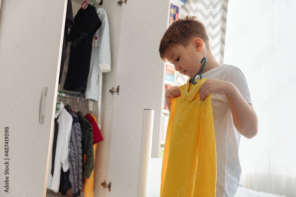 Foto de Stock Preteen boy getting ready for school. Cute little boy open the closet wardrobe and ...